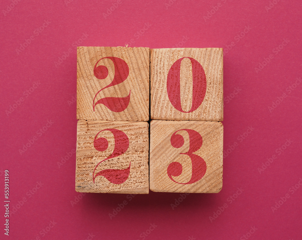 Wooden blocks with the Year number 2023 on a magenta paper sheet, color ...