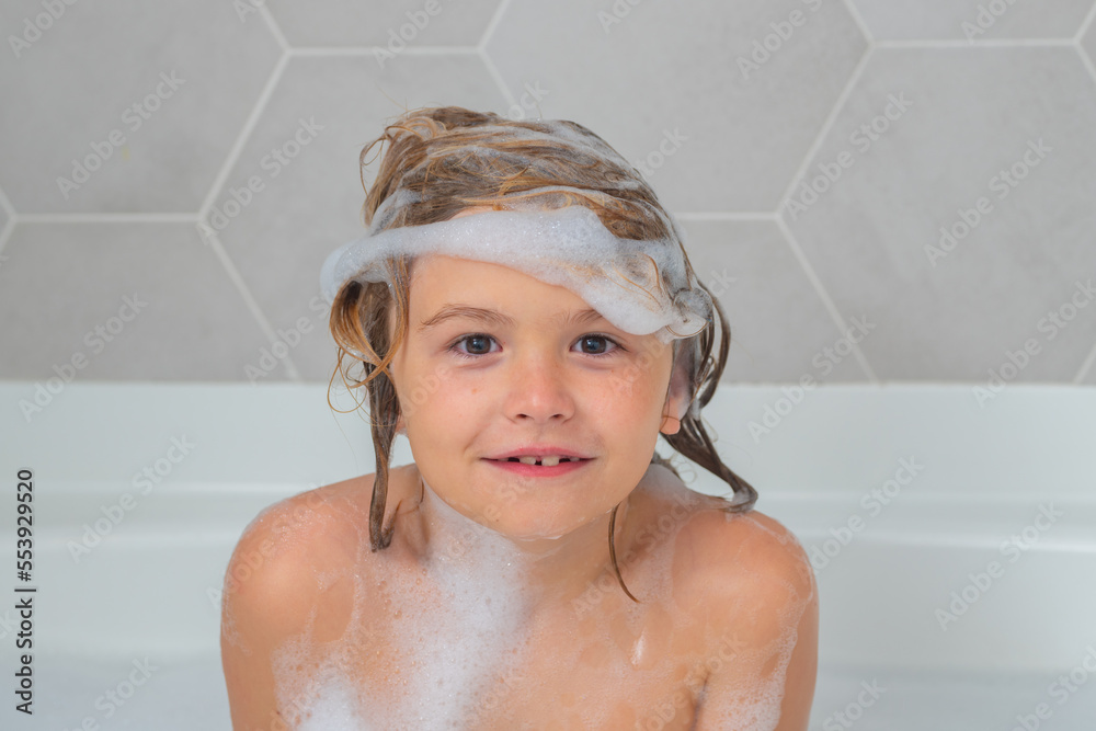 Child with shampoo foam and bubbles on hair taking bath. Funny face of ...