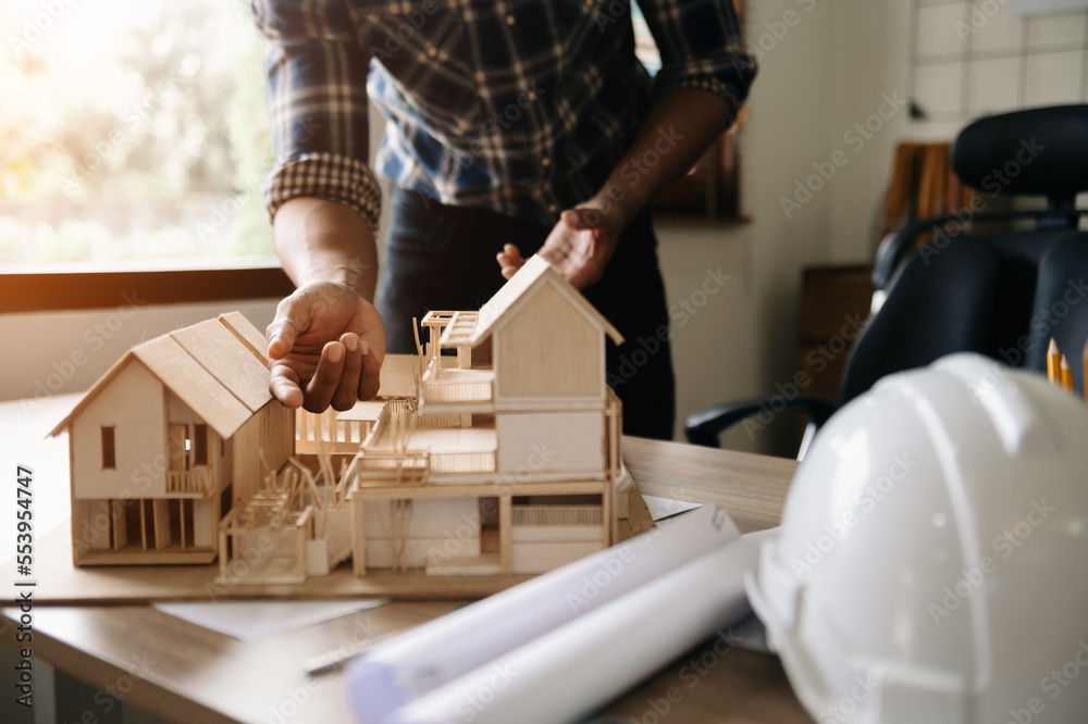 Shot of scale model house on table with architects. Two architects ...