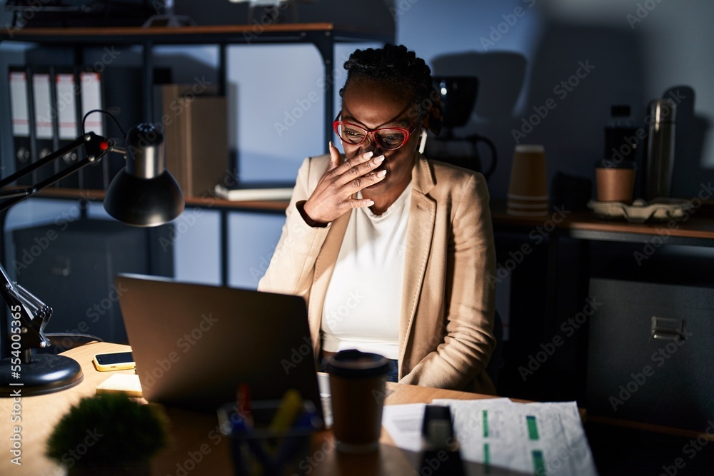 Beautiful black woman working at the office at night smelling something ...