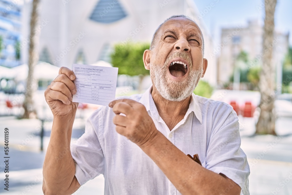 Mature doctor man holding covid record card angry and mad screaming ...