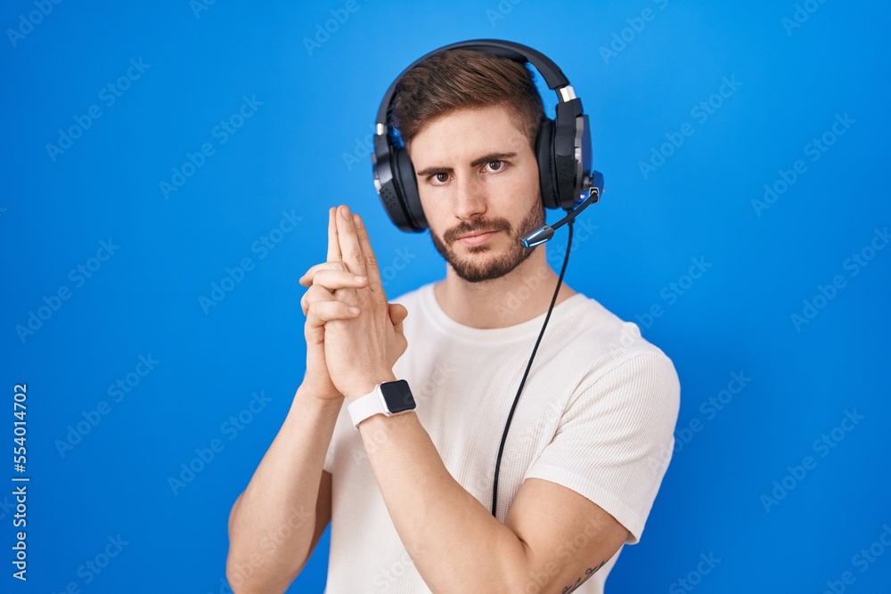 Hispanic man with beard listening to music wearing headphones holding ...