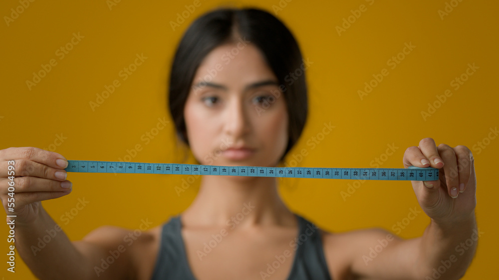 Sad upset worried Indian woman girl in yellow studio with measuring ...