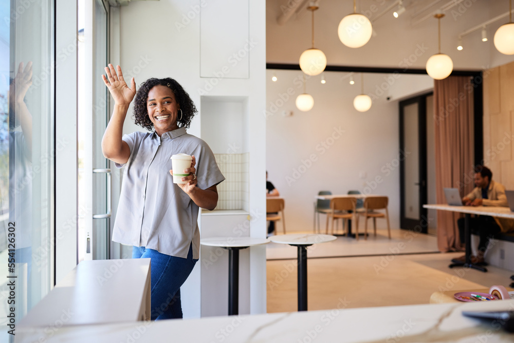 Happy woman with disposable coffee cup waving while leaving cafe Stock ...