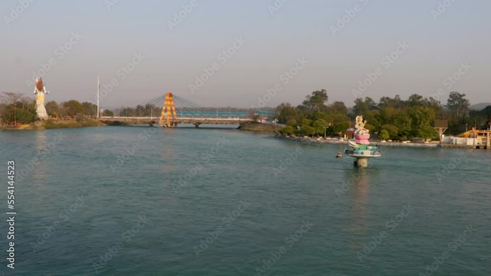 hindu god statue and isolated cable bridge over ganges river from back ...