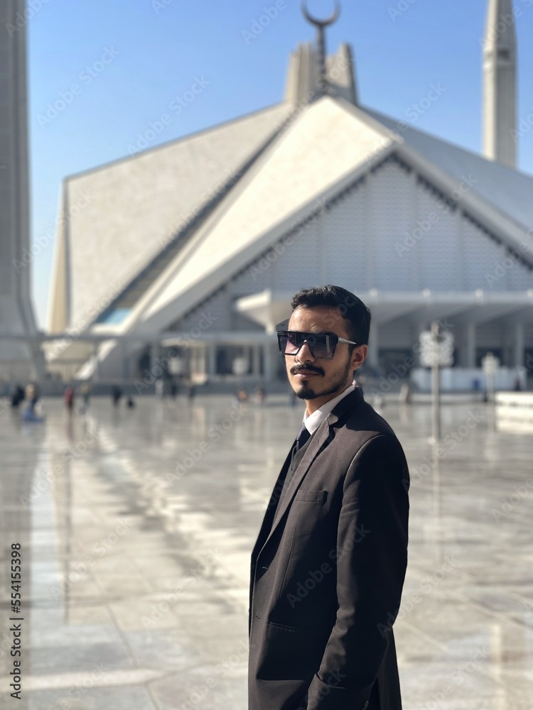 A young person standing in front of faisal mosque in Islamabad, capital ...