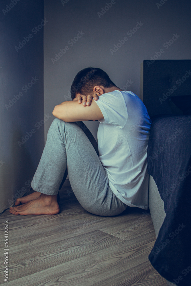Depressed man sitting on the floor with his head down and leaning ...