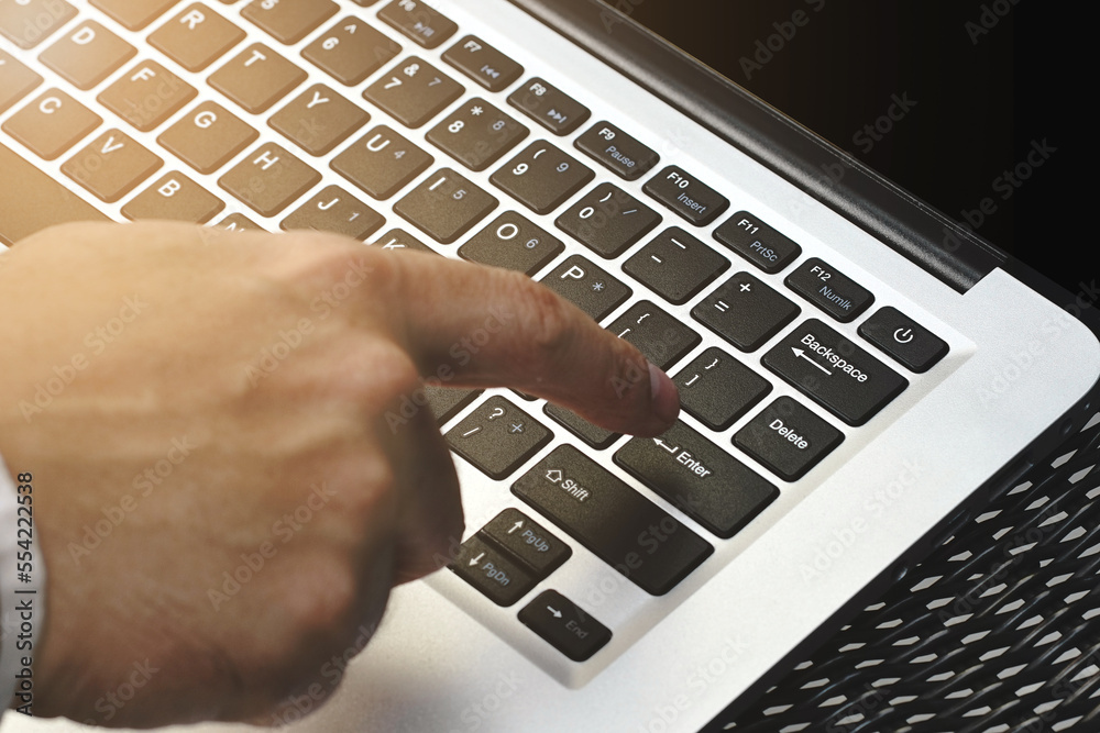 Businesssman hand touching enter button on Laptop keyboard with sun ray ...