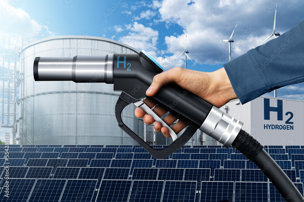 Hand with hydrogen fueling nozzle on a background of H2 factory ...