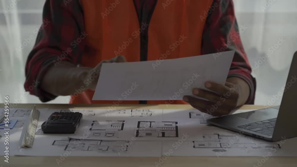 Engineer looking at blueprints and planning building construction on ...
