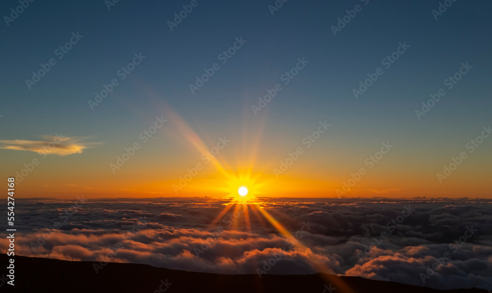 Haleakala at sunset with dramatic golden sun rays shining bright over ...