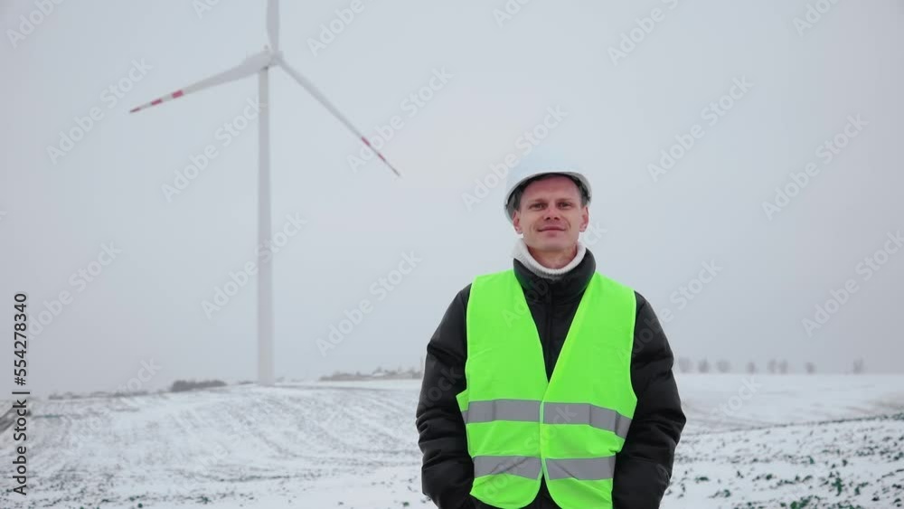 Engineer man in uniform and security helmet smiling stand near rotating ...