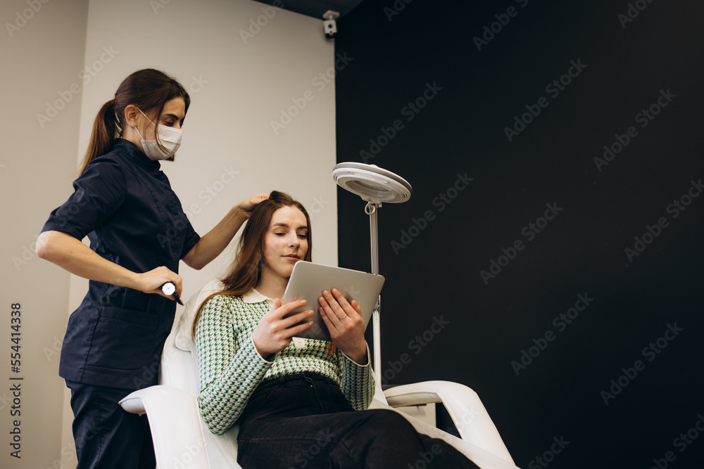 Doctor examines head skin of a young girl with special dermatology ...