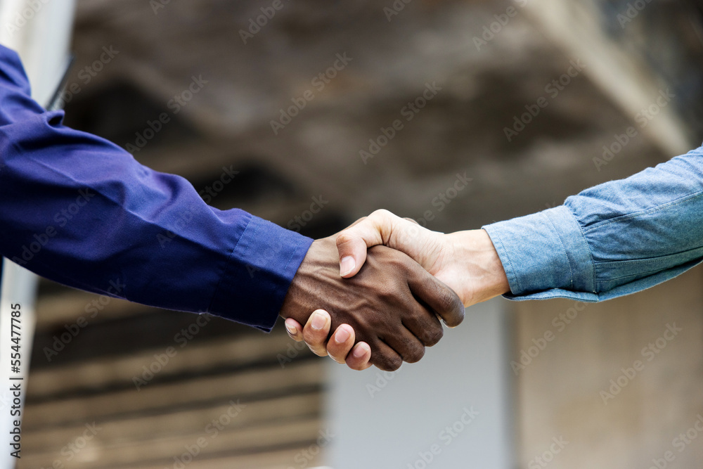 construction workers shaking hands together with co-workers ...