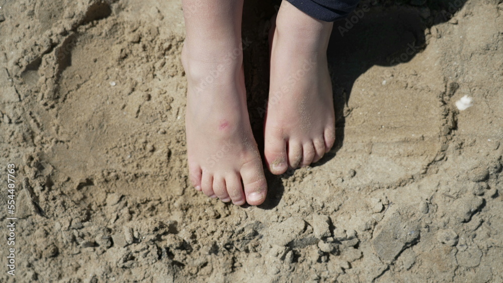 Child feet standing up at beach feeling the sand barefoot. Kid foot ...