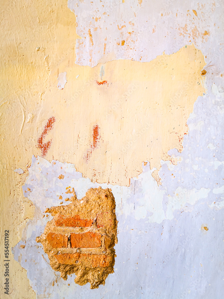 A wrecked brick wall with loose layer of plaster. Broken wall with ...