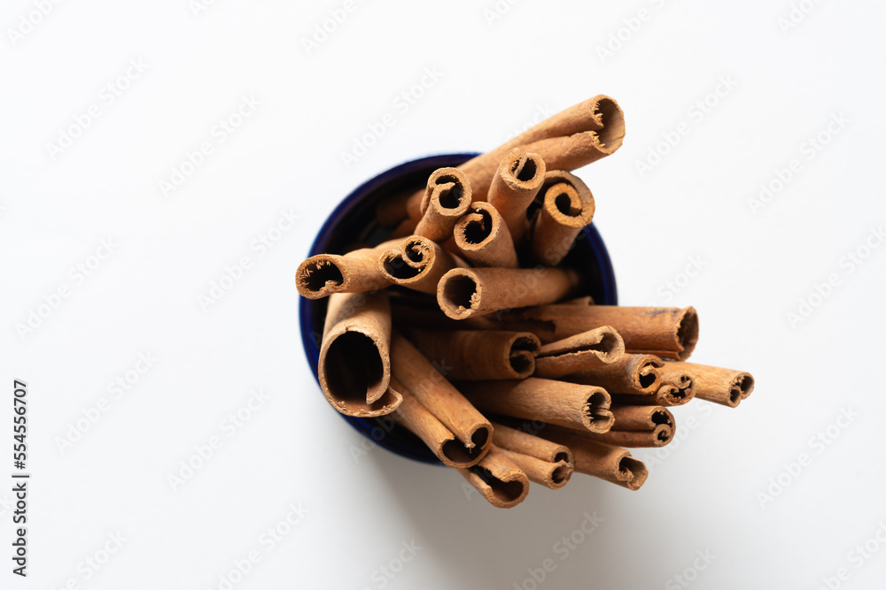 cinnamon sticks in a round dish viewed from the top on a white ...