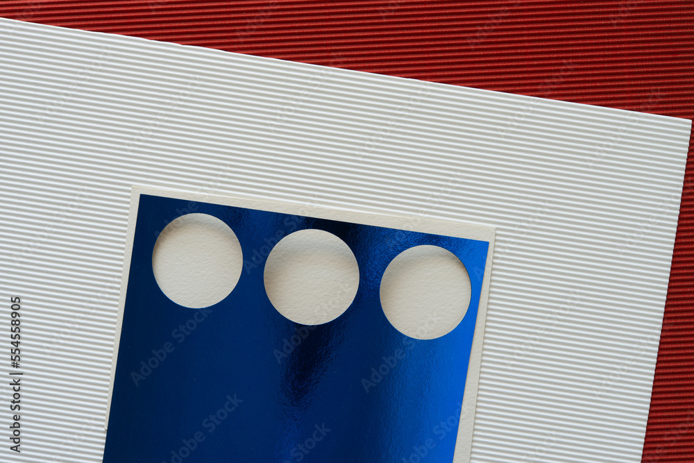 blue foil cardboard with three holes on white and red corrugated paper ...