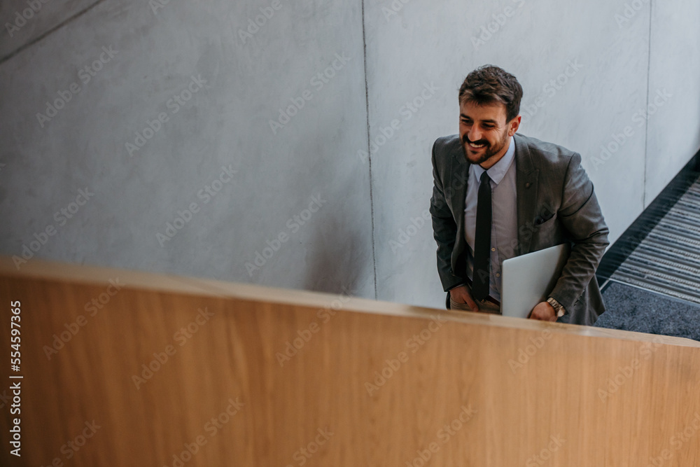 Smiling executive climbing up the stairs in the office building ...