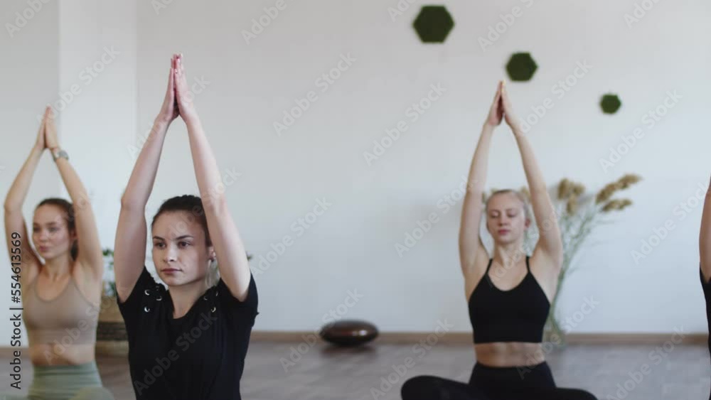 Group of caucasian fit girls doing yoga class meditating together ...
