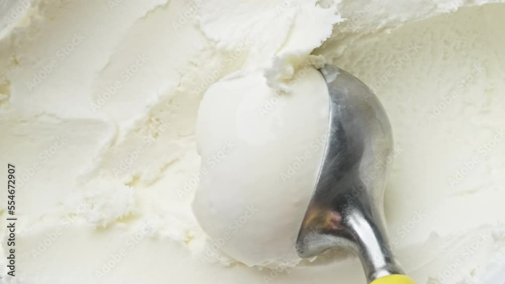 Delicious ice cream scooping out of container by spoon. Vanilla ice ...