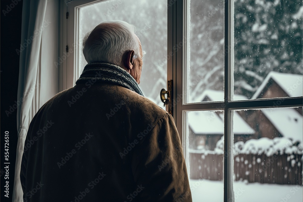Lonely old man looks out the window at the first winter snow, back view ...