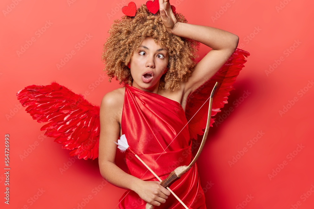 Surprised curly haired lady makes grimace keeps mouth opened wears ...