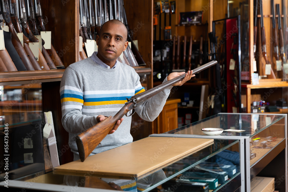 Portrait of hispanic salesman showing collectible old rifled musket on ...