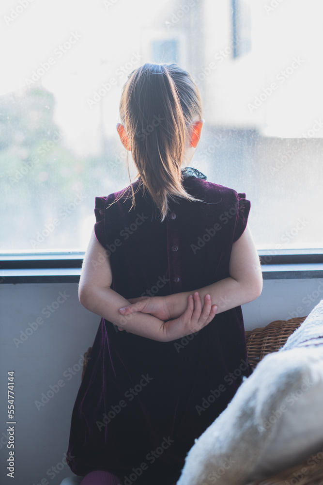 back view of little girl looking at the window Stock Photo | Adobe Stock
