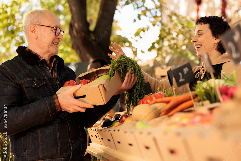 Cheerful woman giving box full of fresh fruits and veggies to elderly ...