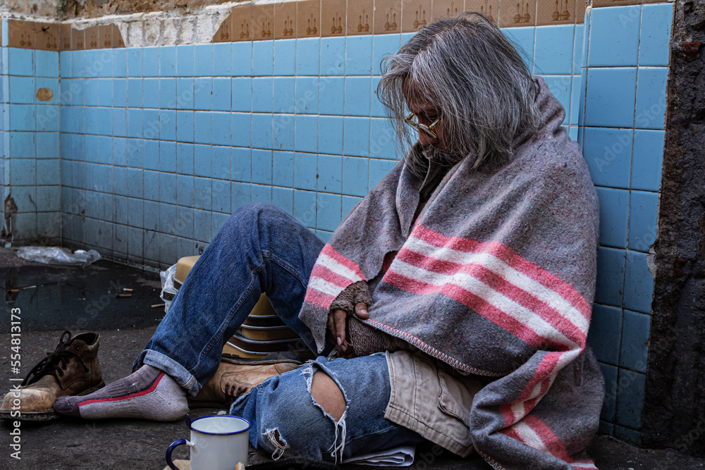 Retirement aged man with an old blanket sitting on roadside feel tired ...
