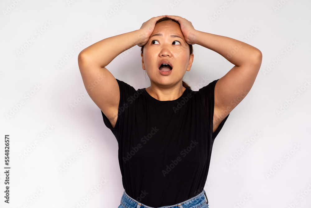 Portrait of frustrated young woman holding head in hands over white ...