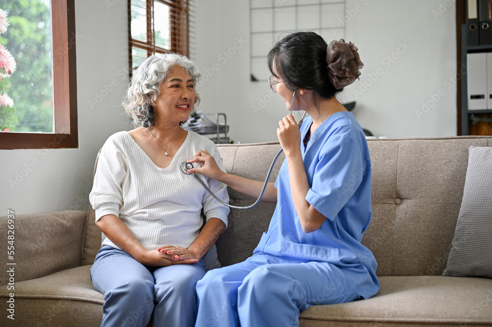 Professional Asian female doctor visiting her retire female patient at ...