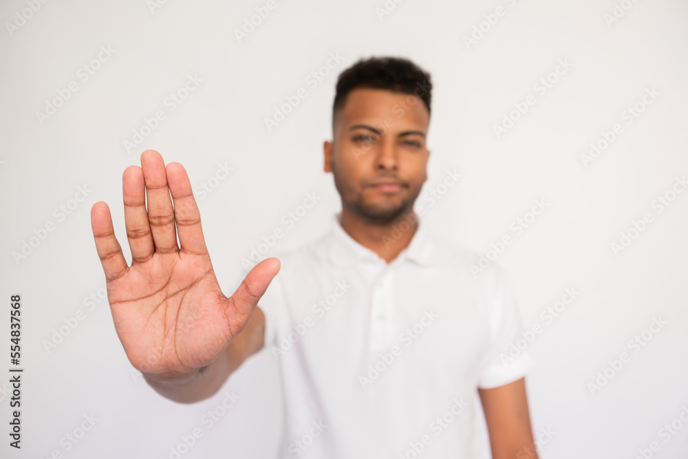 Close-up of stop sign made by serious young man. Male Indian model with ...