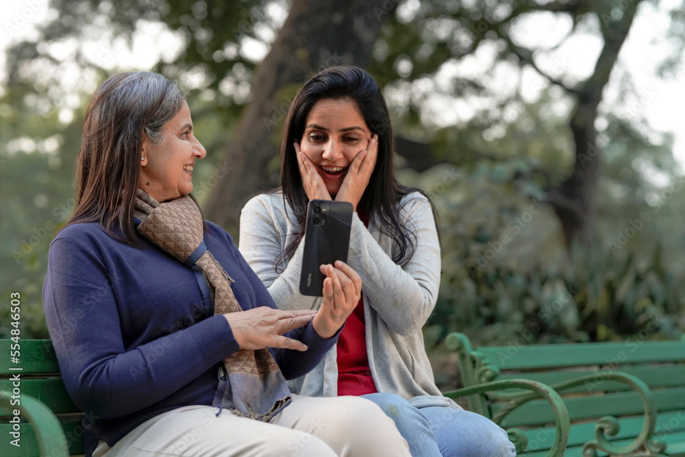 Two indian woman in warm wear and talking on video call at park. Stock ...