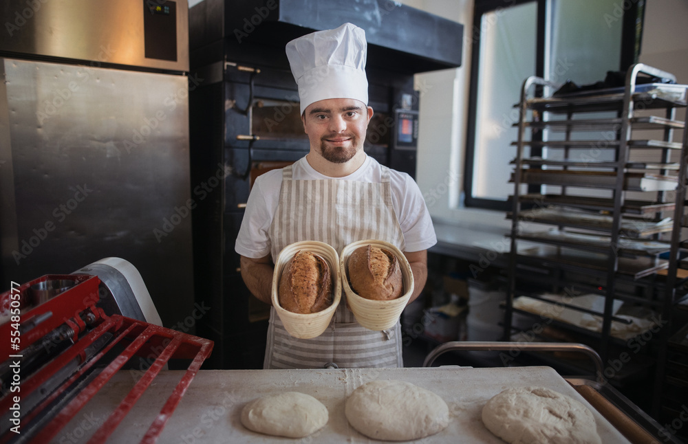 Young baker with down syndrome preparing pastries in bakery. Concept of ...