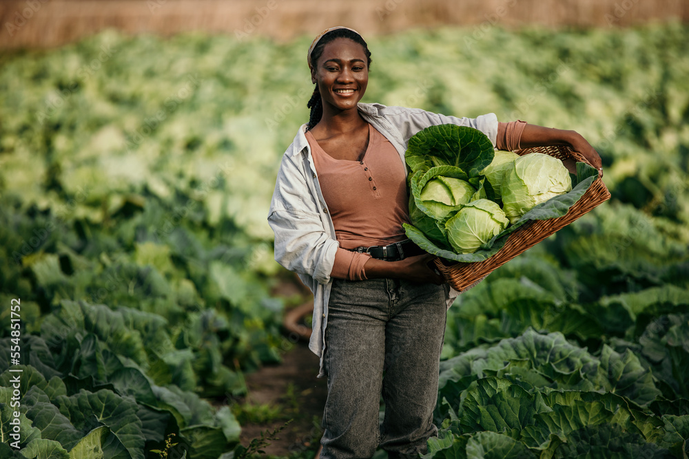 Shot of an attractive young female farmer carrying a crate of fresh ...