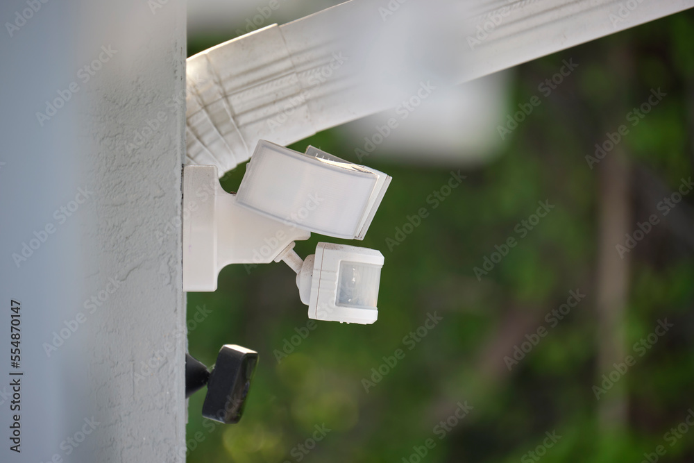 Motion sensor with light detector mounted on exterior wall of private ...
