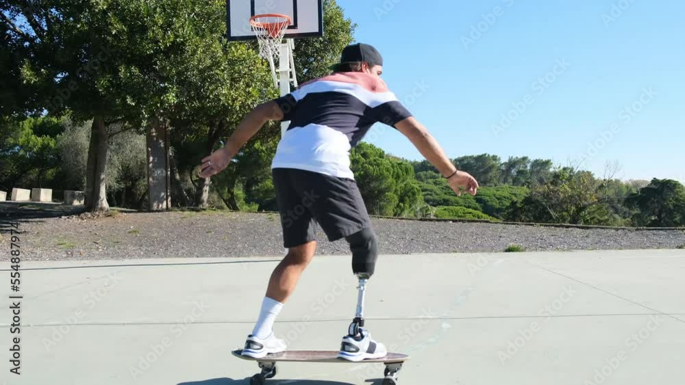 Sporty man with leg prosthesis stepping on skateboard and pushing off ...