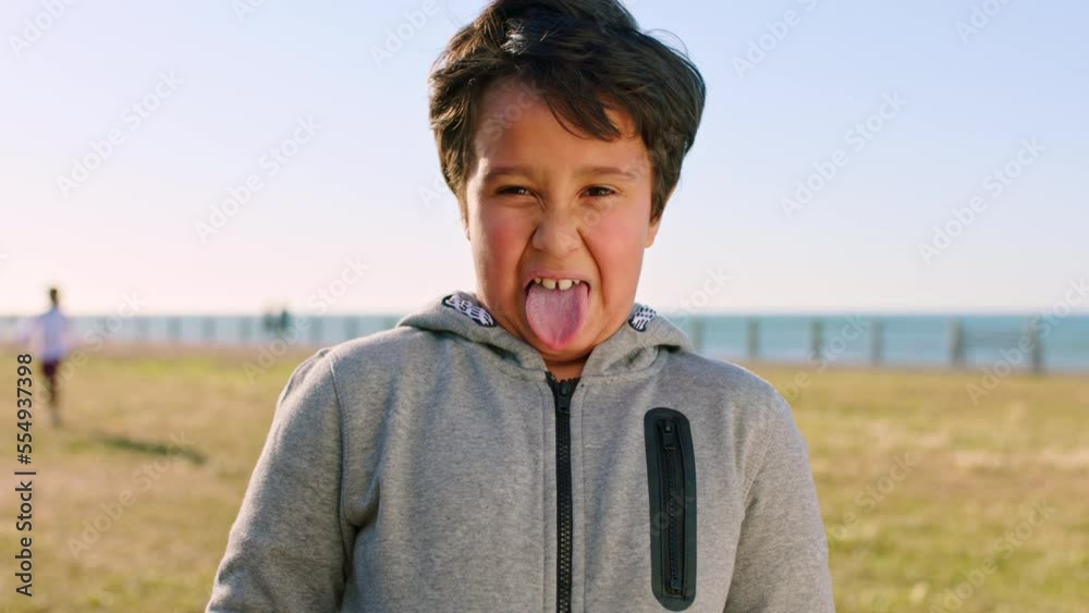 Cild, funny face and beach park with tongue out for disgust and gross ...