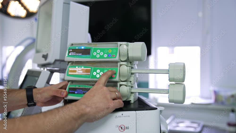 Male hands press and hold the buttons of a syringe infusion pump. The ...