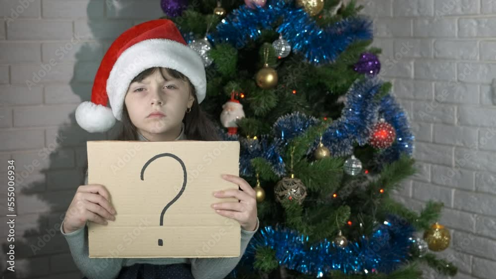 Confused child in Christmas hat. A confused young girl in red Santa hat ...