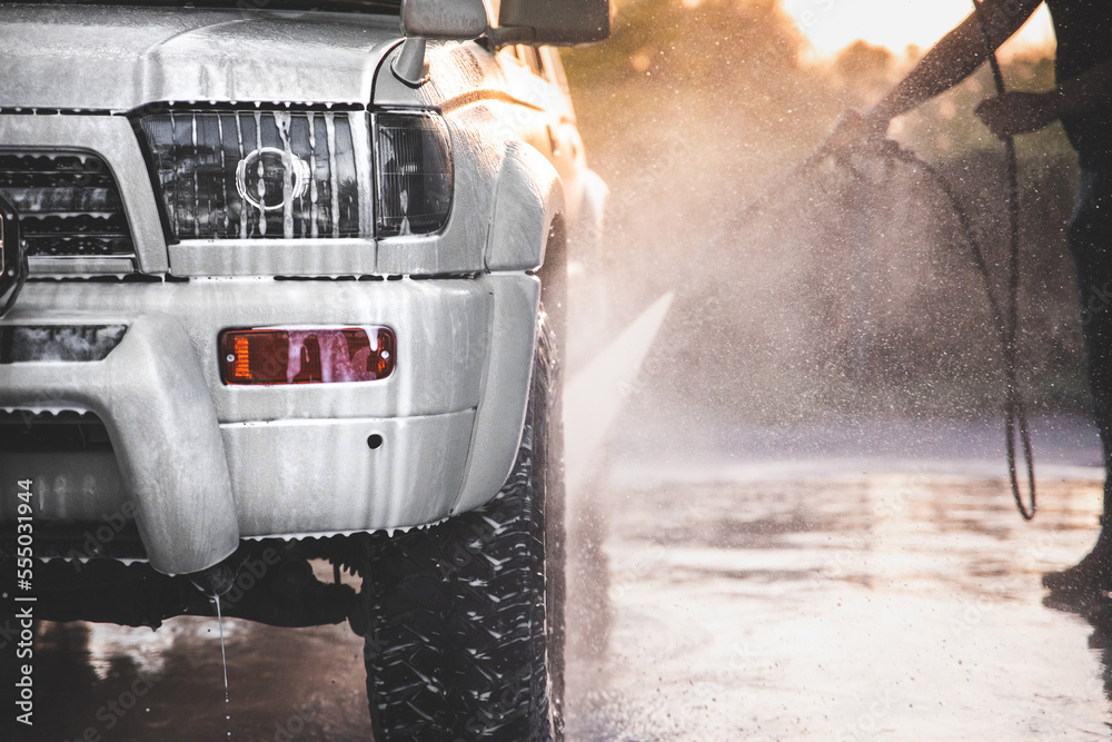 Washing white car at a self-service car wash with a high-pressure water ...