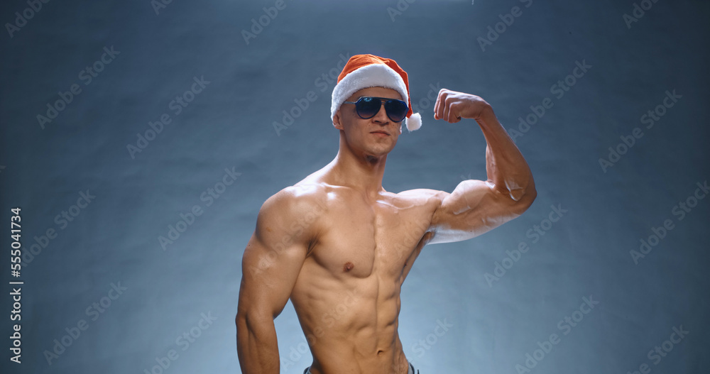 Strong bodybuilder with Santa Claus Hat and with dark glasses ...