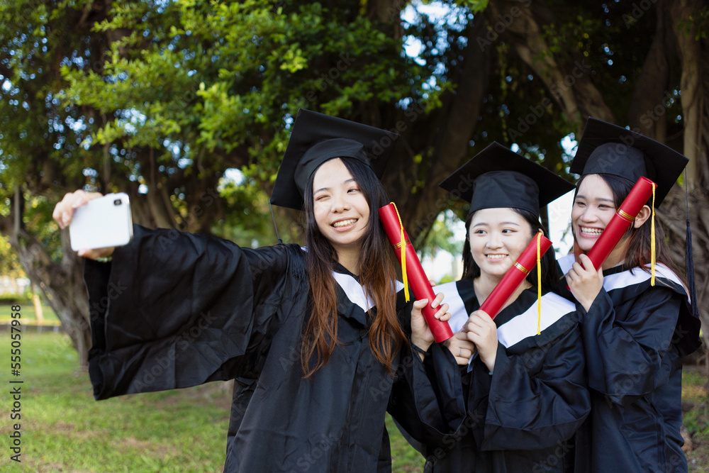 Asian students in graduation gowns with diplomas standing and ...