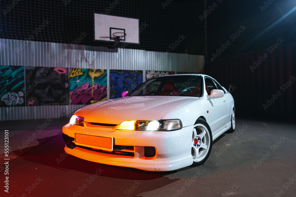 90s sport car with smoke in neon light on the asphalt road at night ...