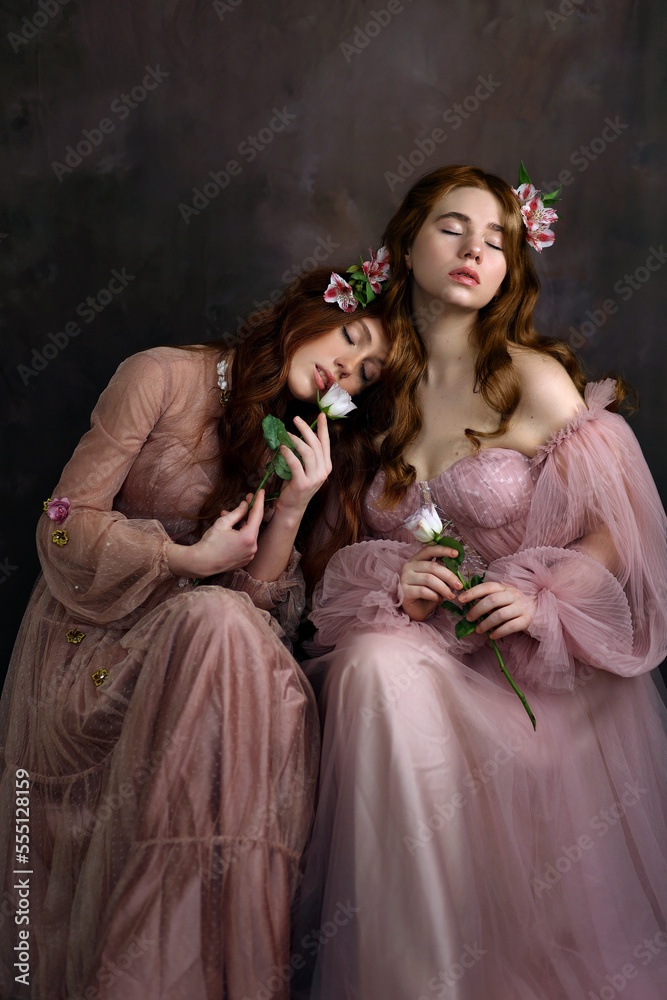 Two red haired young women in pink fairy dresses and pink flowers in ...