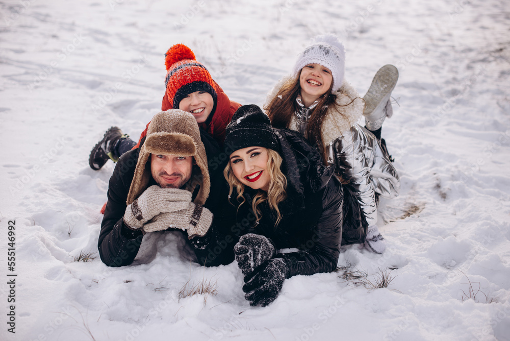 Happy family have fun in winter forest. Mother, father, son and dauther ...