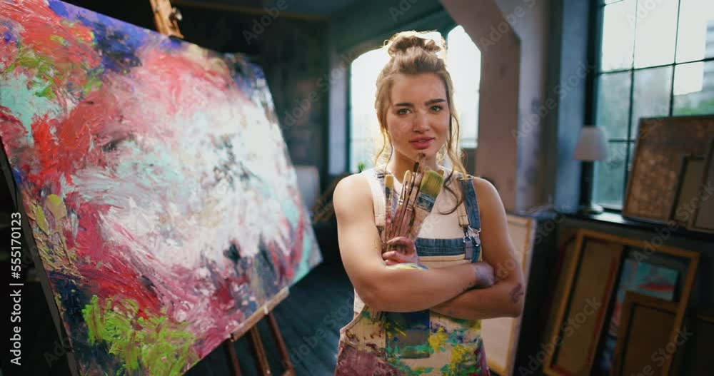 Portrait of female artist in studio next to abstract masterpiece ...