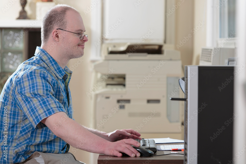 Man with Down Syndrome working at a computer in an office Stock Photo ...